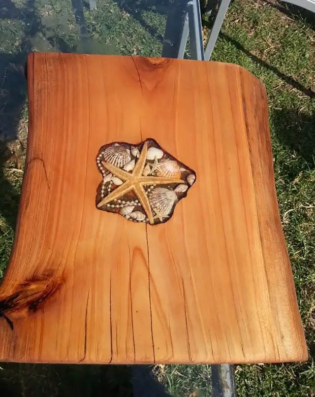 Les artistes remplissent les fissures dans les tables avec des coquillages, des cailloux et des coquilles d'étoiles de mer, table, artiste